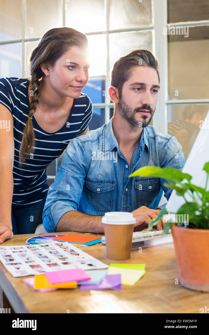 Smiling colleagues working together on computer Stock Photo - Alamy