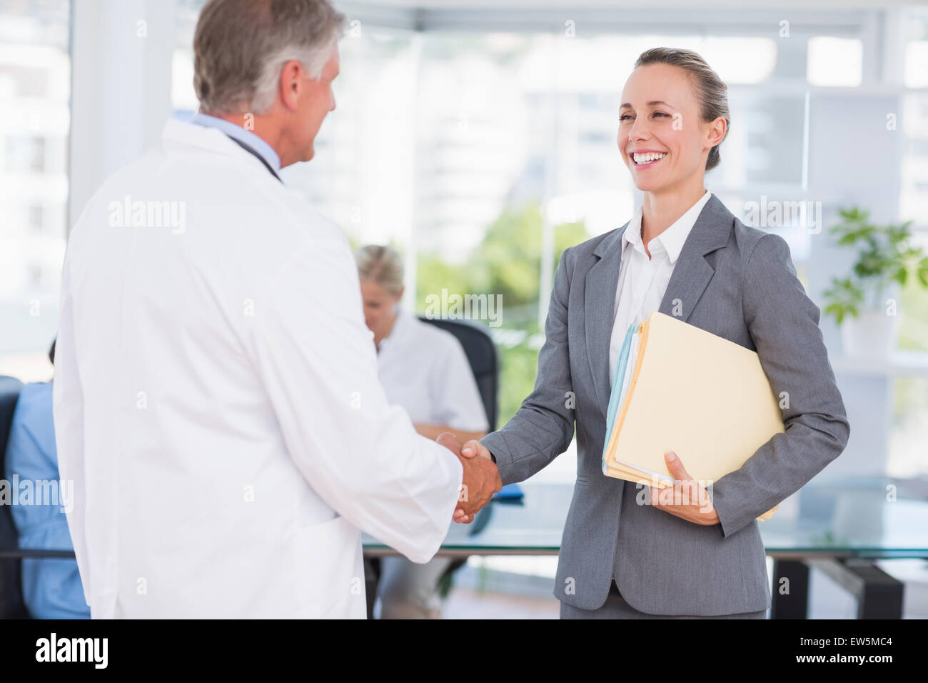 Confident doctor greeting pretty businesswoman Stock Photo - Alamy