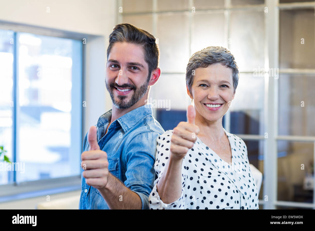 Smiling team standing thumbs up Stock Photo - Alamy
