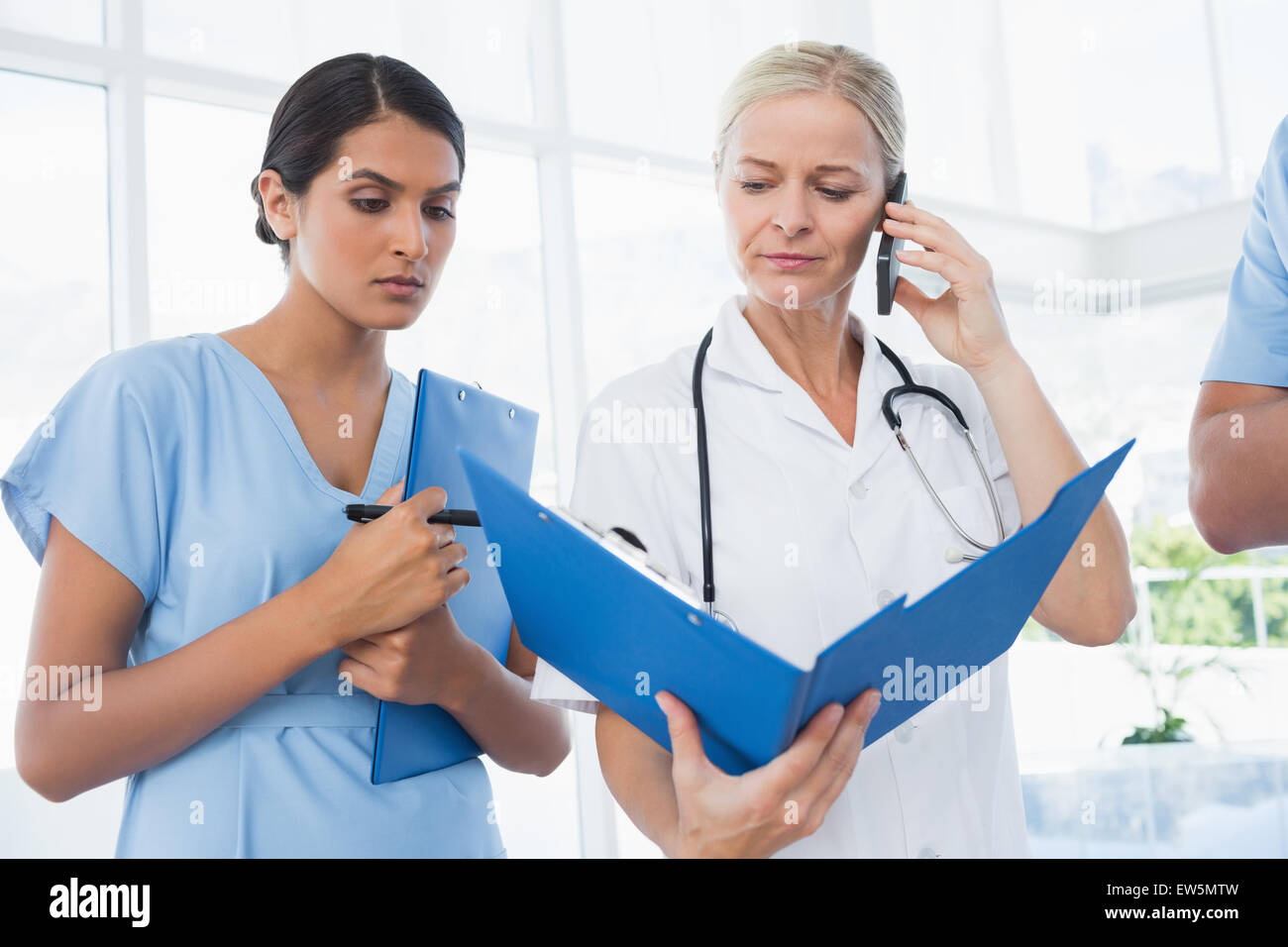 Doctor holding folder and having phone call Stock Photo - Alamy