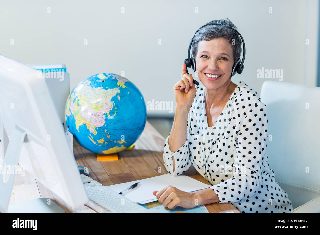 Smiling travel agent sitting at her desk Stock Photo - Alamy