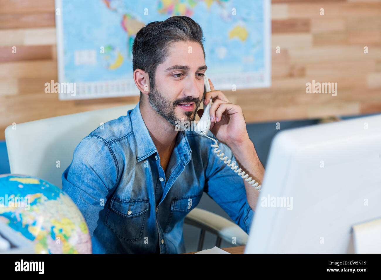 Smiling travel agent having phone call Stock Photo - Alamy