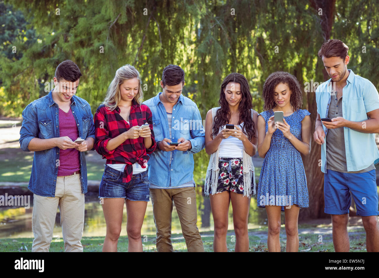 Happy friends in the park using their phones Stock Photo - Alamy