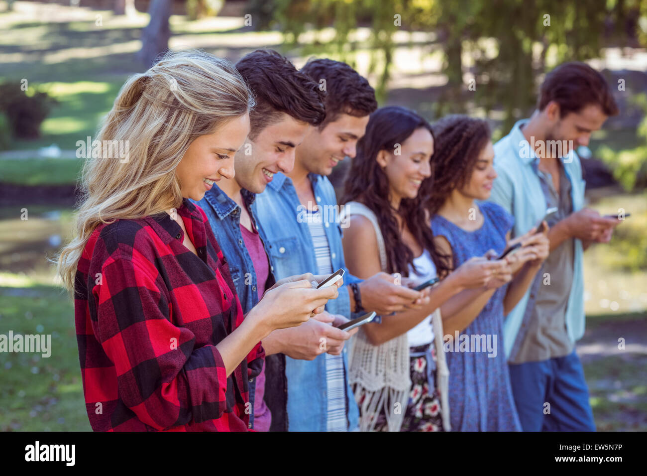 Happy friends in the park using their phones Stock Photo - Alamy