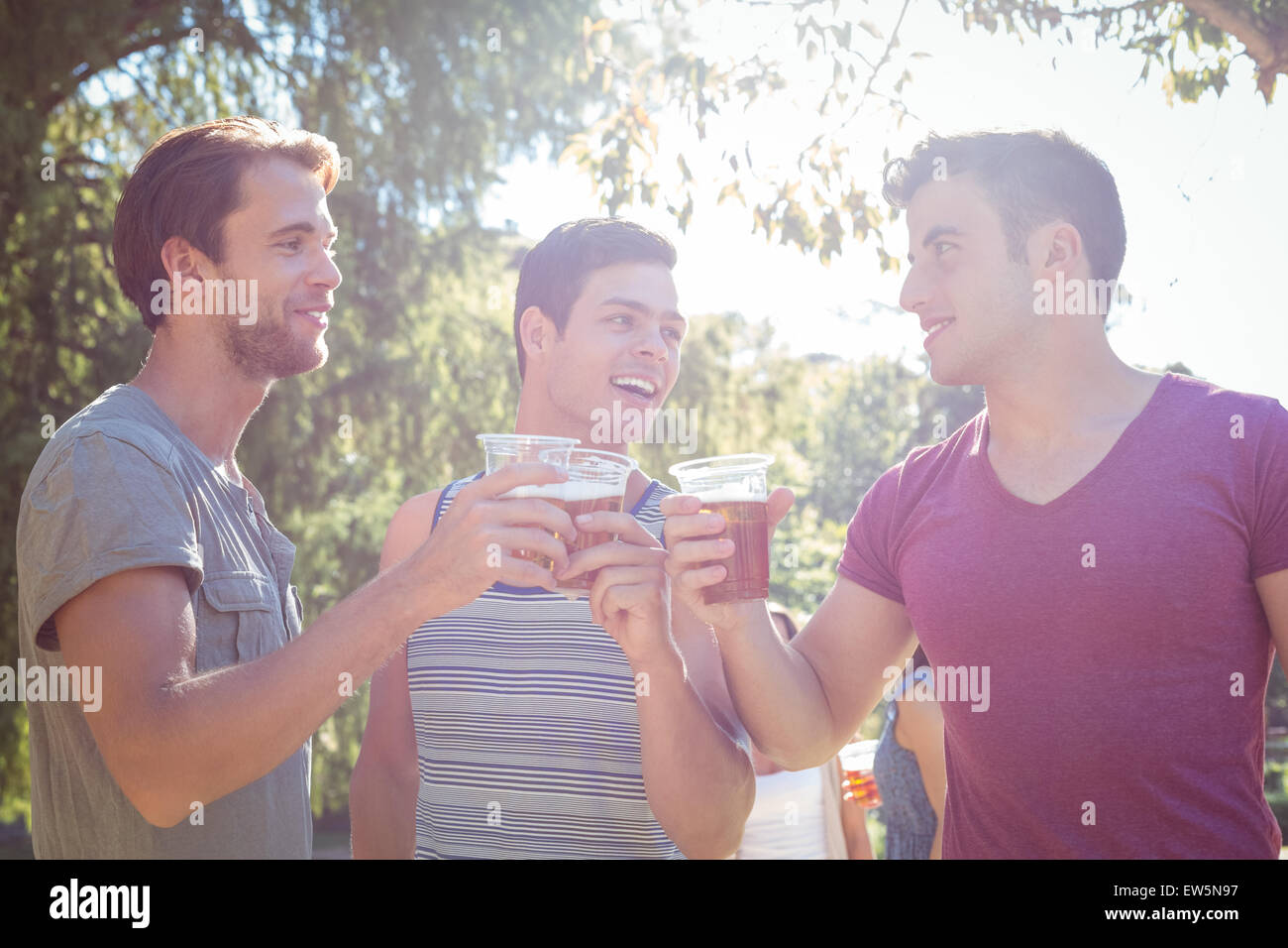 Happy friends in the park having beers Stock Photo - Alamy