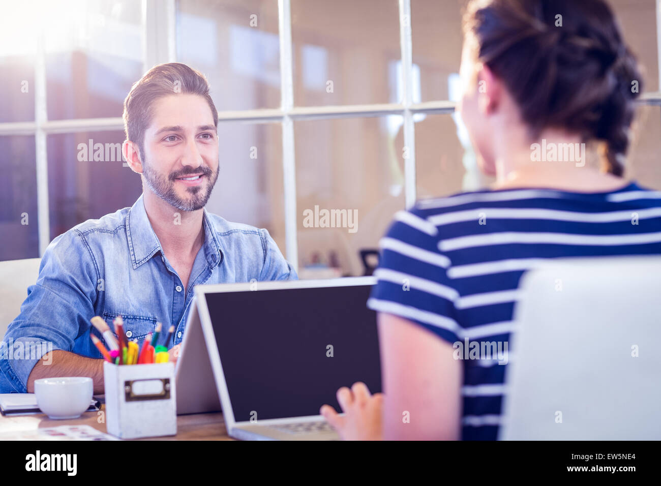 Happy creative workers sharing desk Stock Photo - Alamy