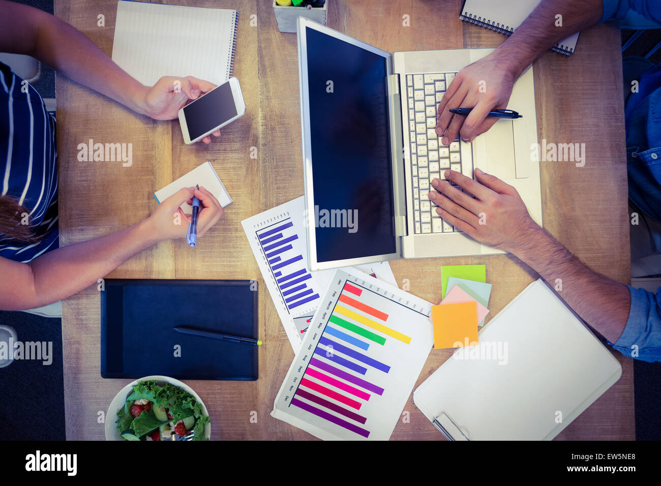 Creative workers sharing desk Stock Photo - Alamy