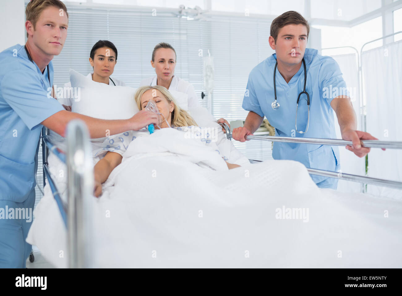 Team of doctors carrying patient on stretcher Stock Photo - Alamy