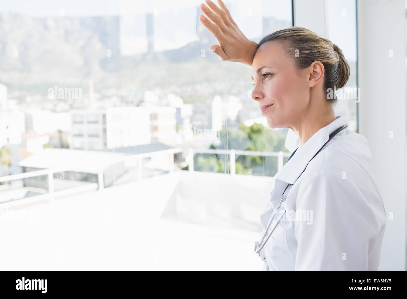 Confident female doctor looking through windows Stock Photo - Alamy