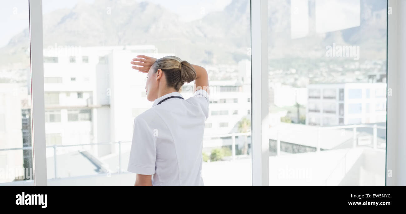 Wear view of confident female doctor looking through windows Stock ...