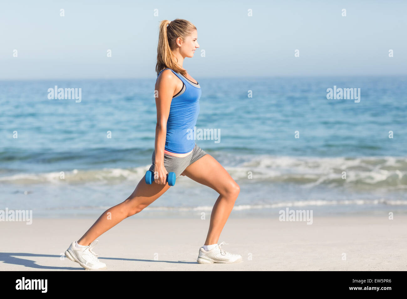 Beautiful fit woman stretching with dumbbells Stock Photo - Alamy