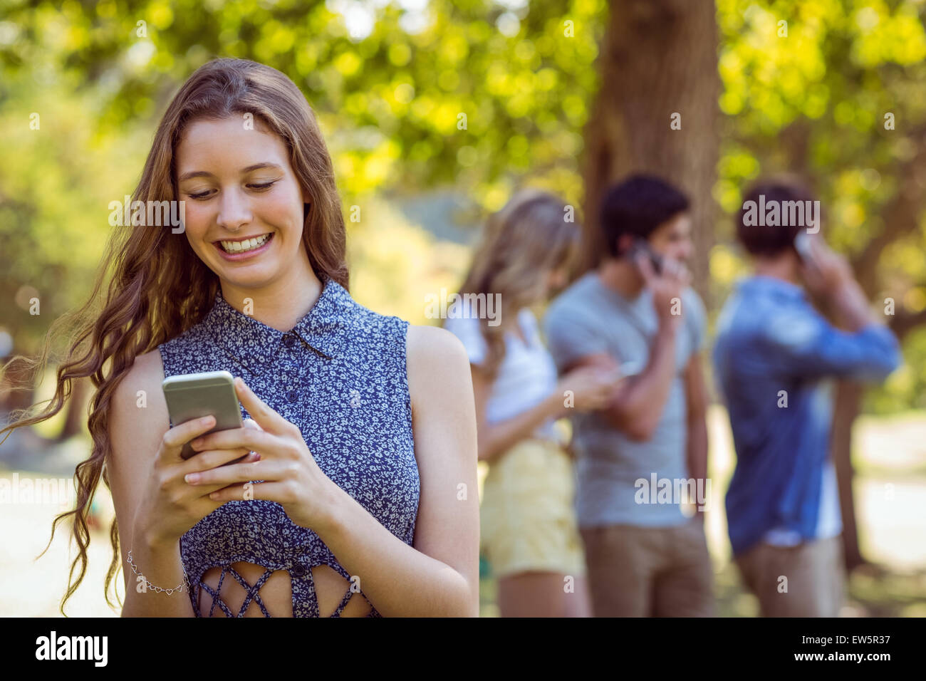 Happy friends in the park using their phones Stock Photo - Alamy