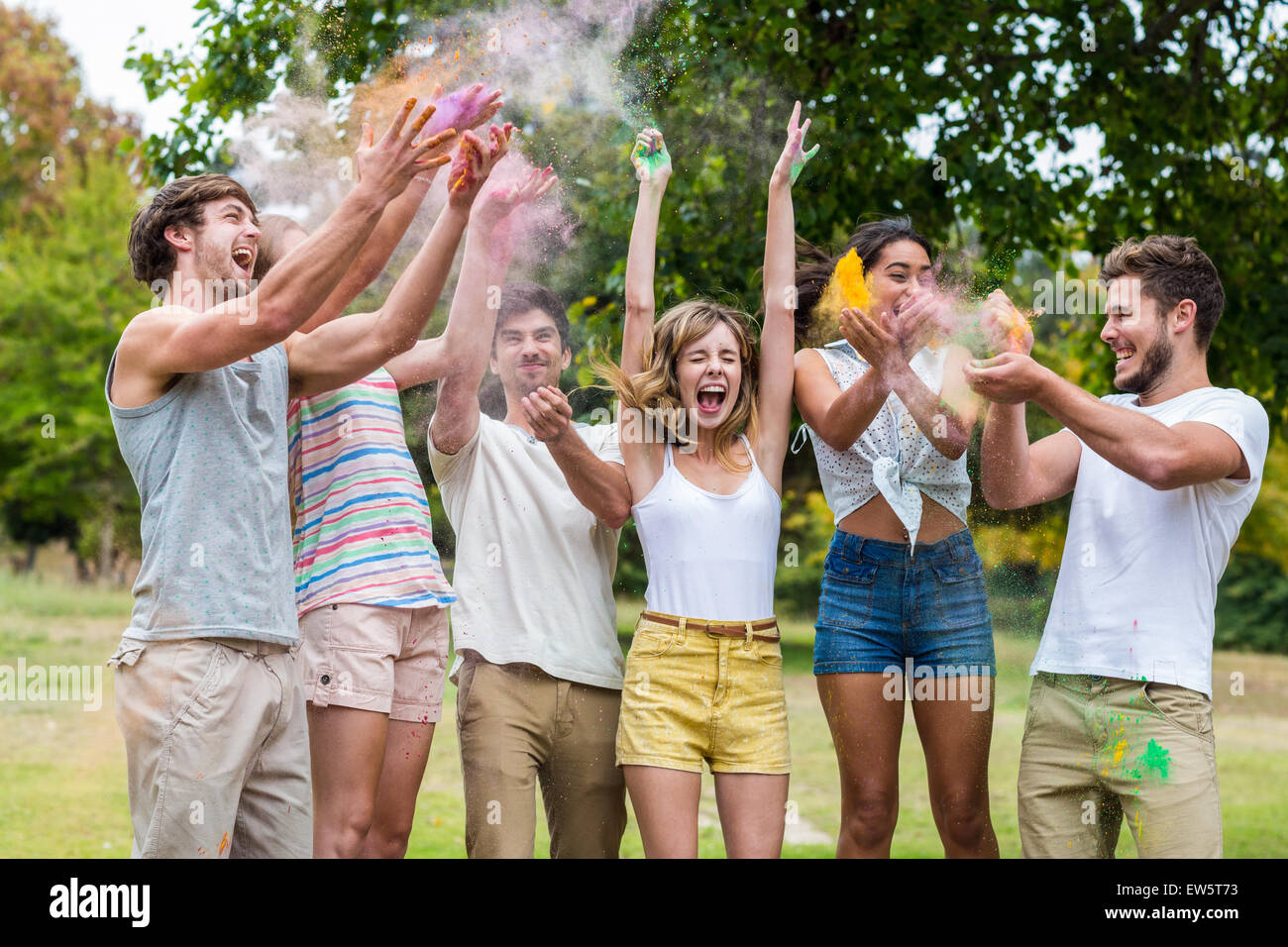 Happy friends throwing powder paint Stock Photo - Alamy