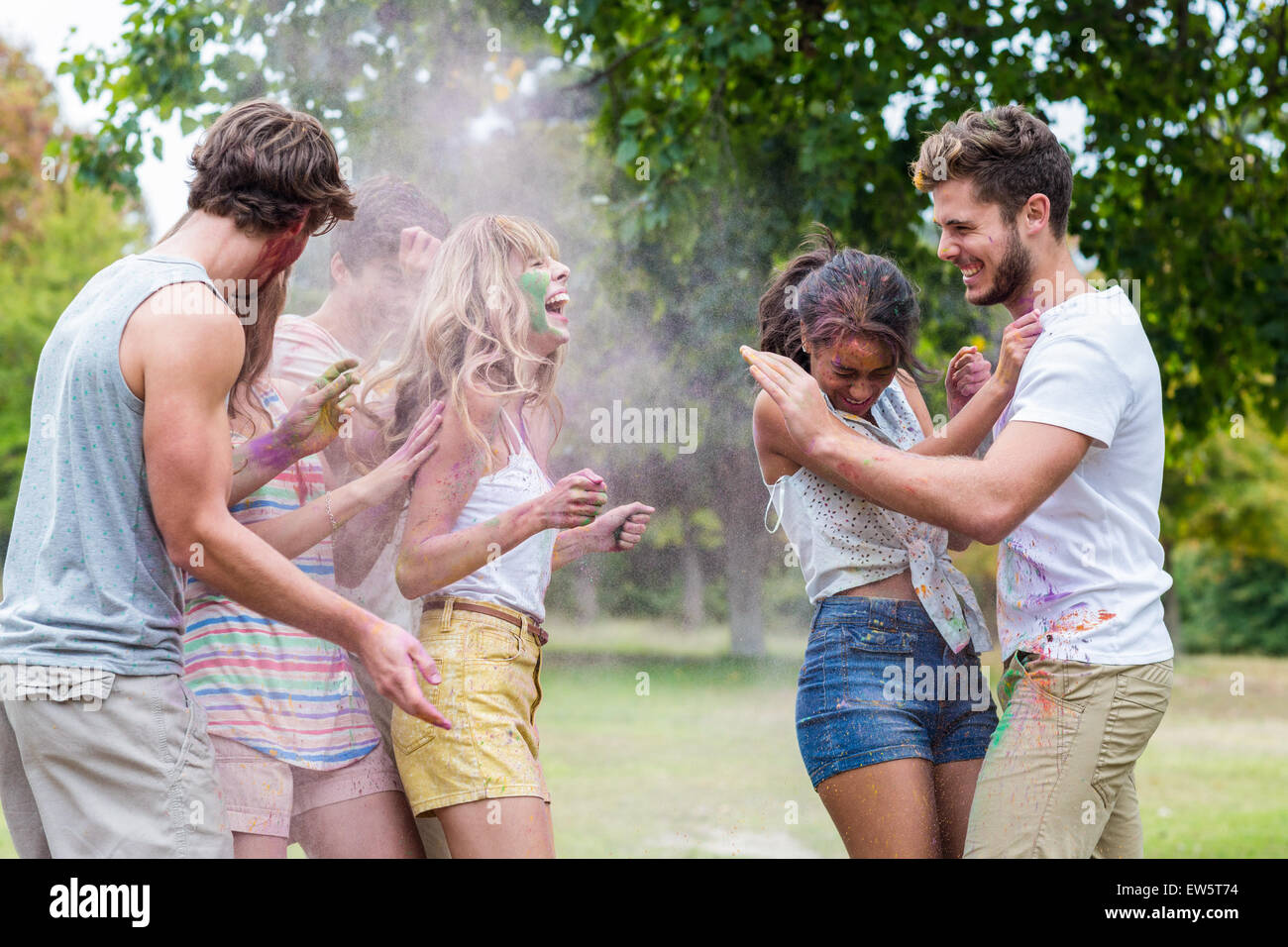 Happy friends throwing powder paint Stock Photo - Alamy