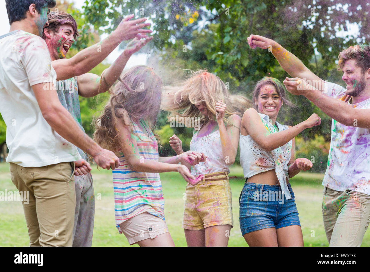Happy friends throwing powder paint Stock Photo - Alamy