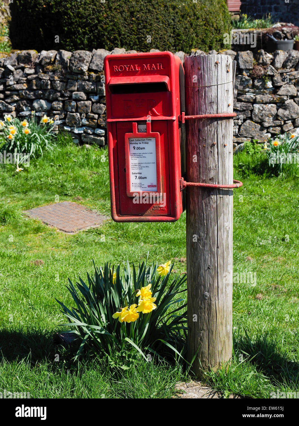 Red post box attached to wooden pole in quaint village of Tissington in ...
