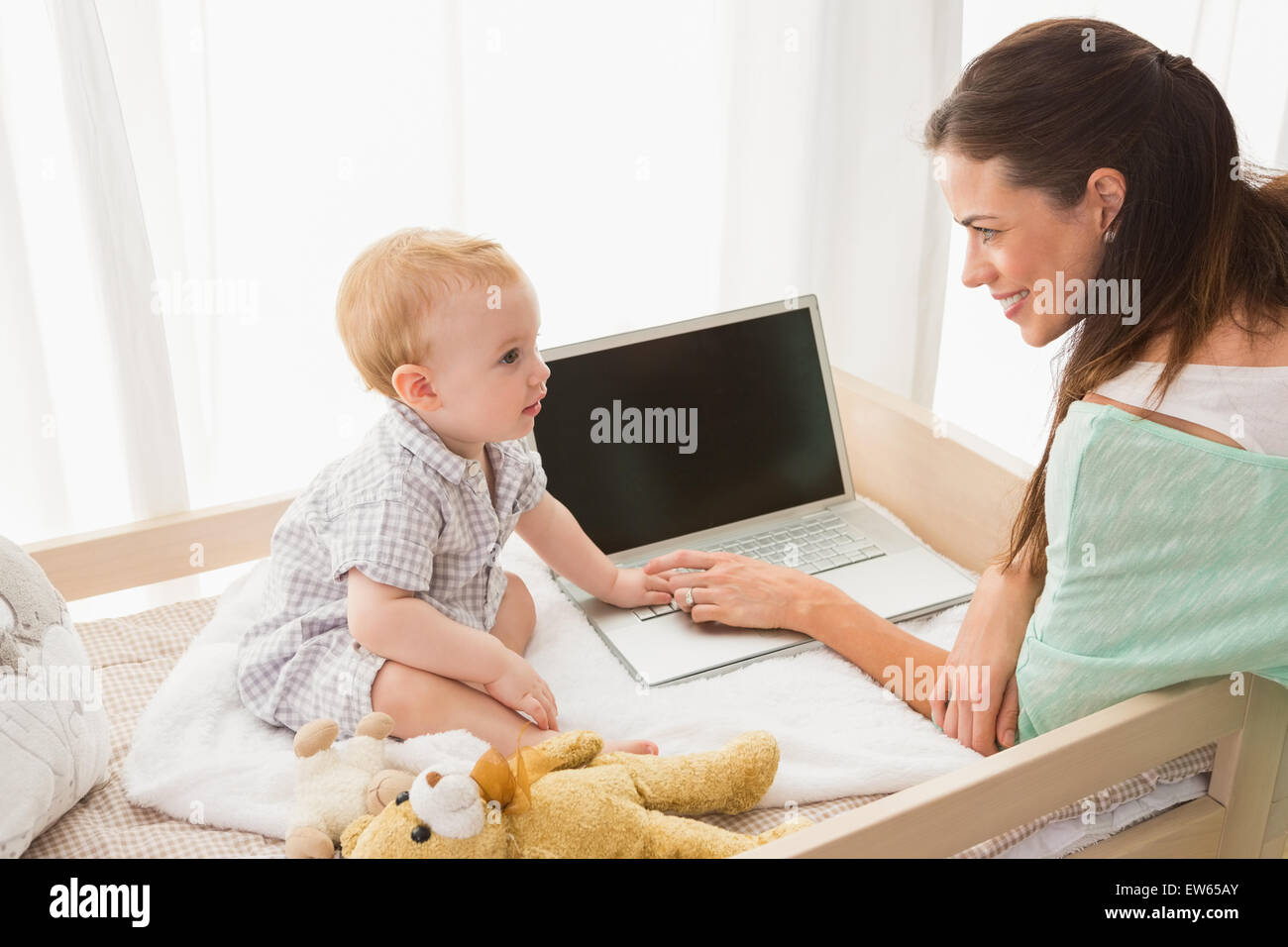 Happy mother using laptop with her baby boy Stock Photo - Alamy