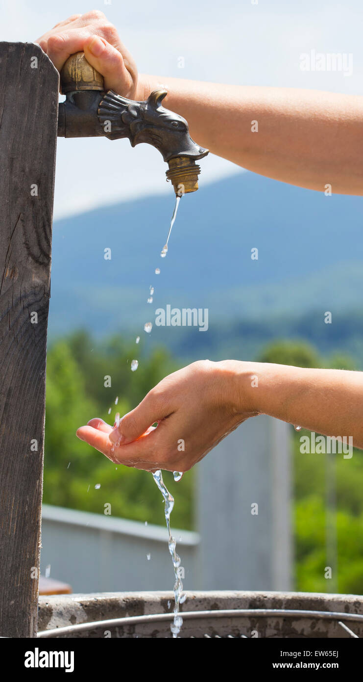 Hand opening a water pipe, water is flowing out Stock Photo - Alamy