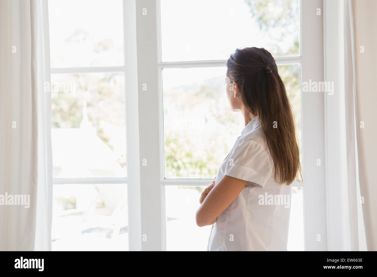 Beautiful brunette woman looking out in the window Stock Photo - Alamy
