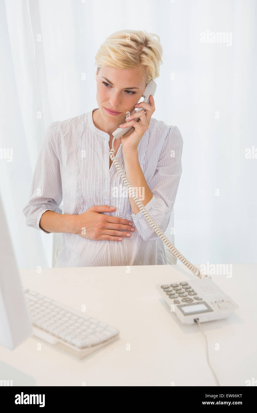Smiling blonde woman using computer and phoning Stock Photo - Alamy