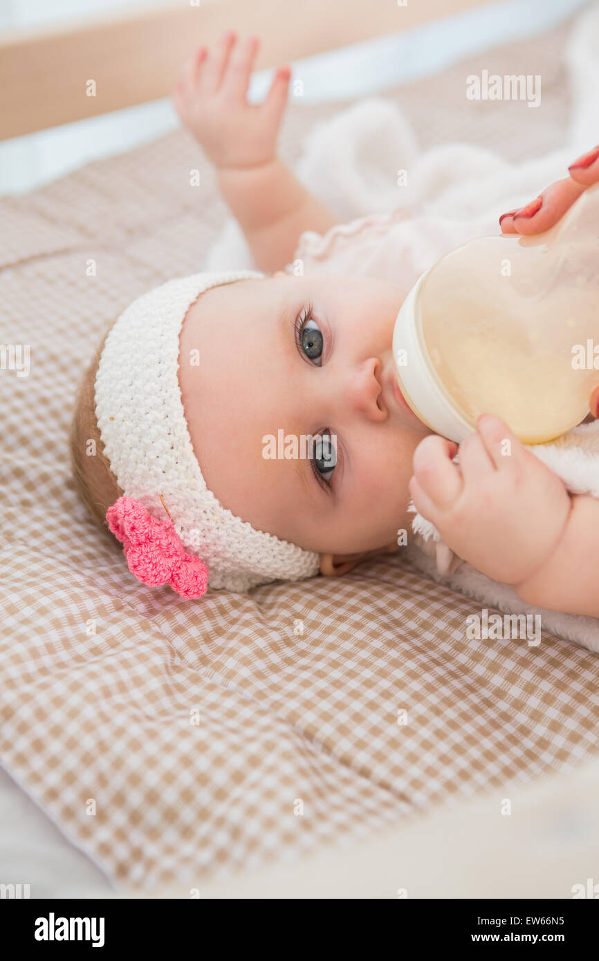 Happy cute baby girl drinking her baby bottle Stock Photo - Alamy