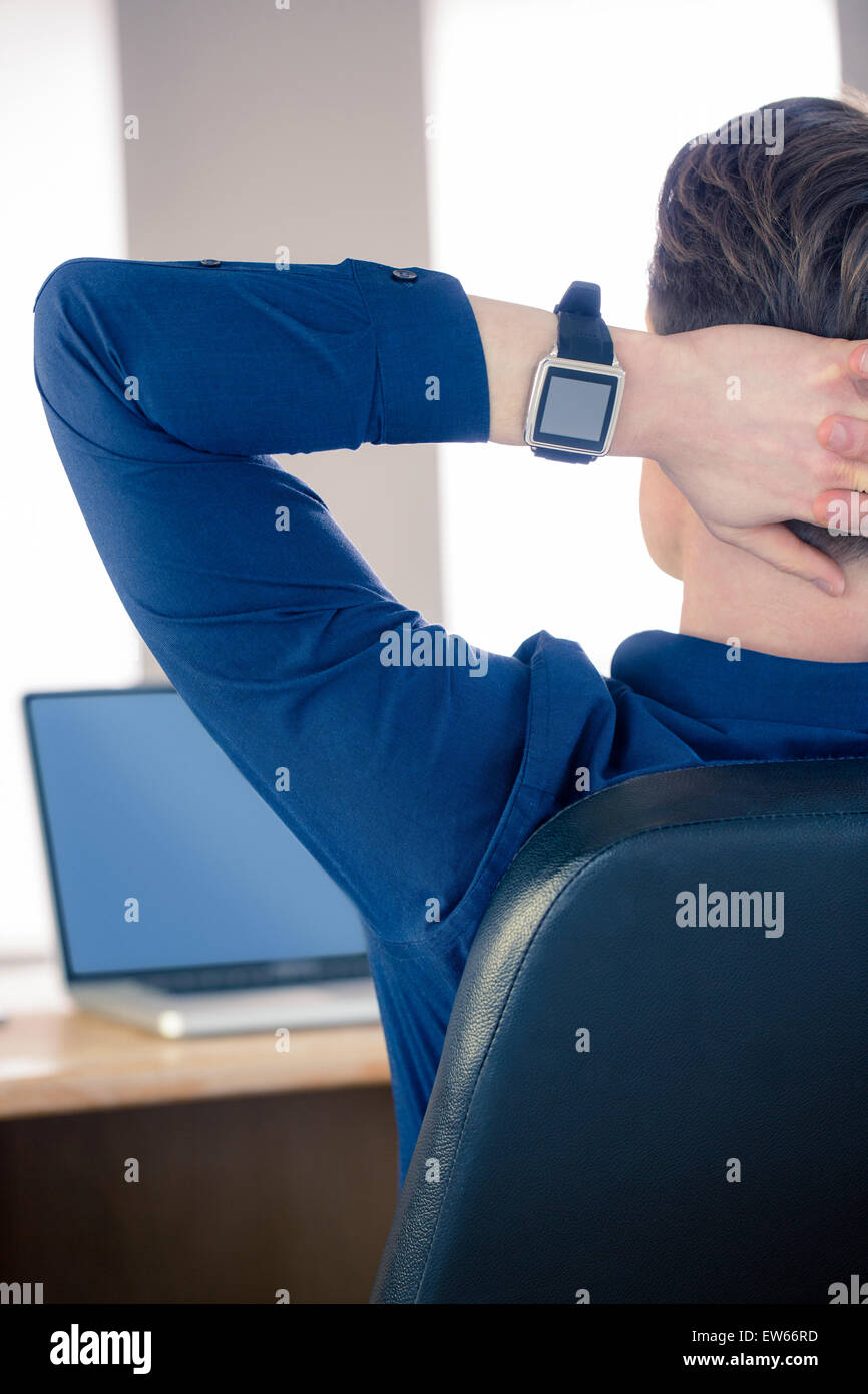 Rear view of businessman relaxing in a swivel chair wearing smartwatch ...