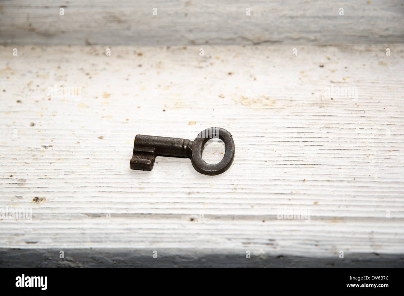 An old rusty key at a dirty white painted wooden surface Stock Photo ...