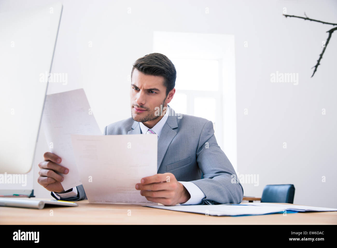 Confident businessman reading papers at his workplace in office Stock ...