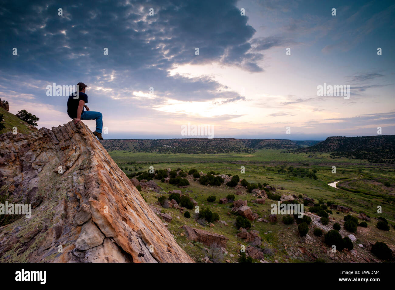 A man looking out over a canyon with a river running through ...