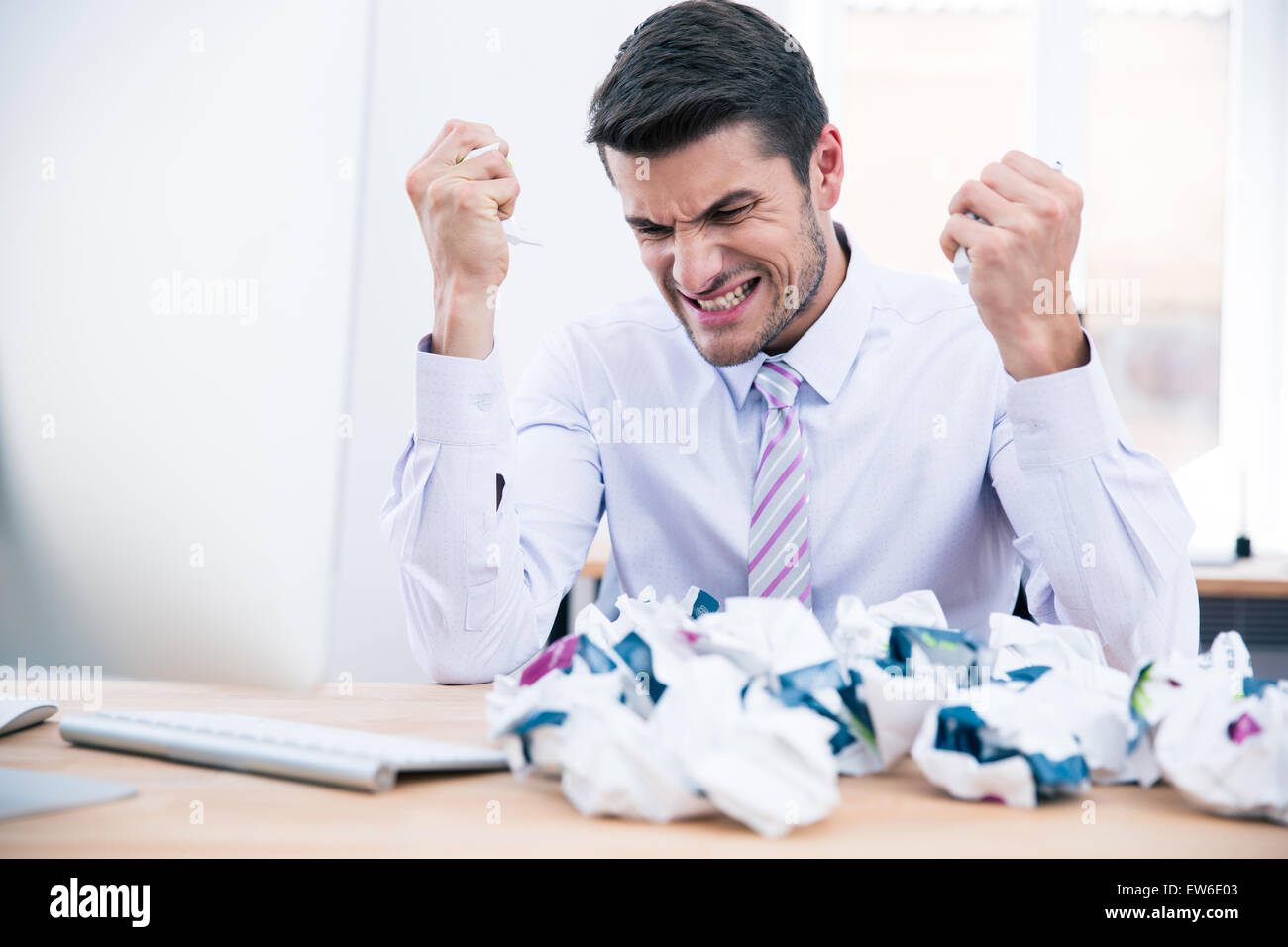 Upset businessman sitting at the table with crumpled paper in office ...