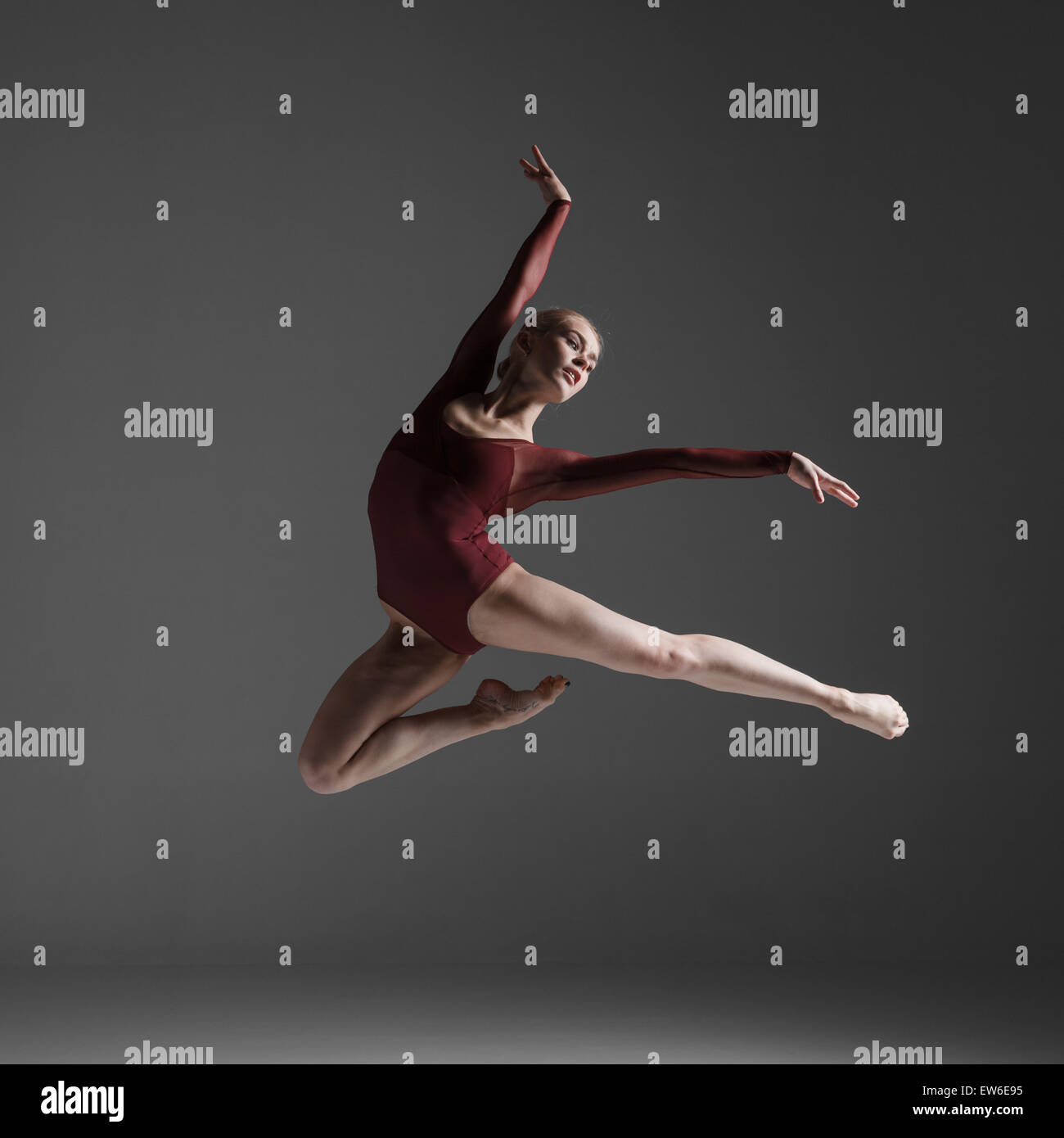 young beautiful modern style dancer jumping on a studio gray background ...