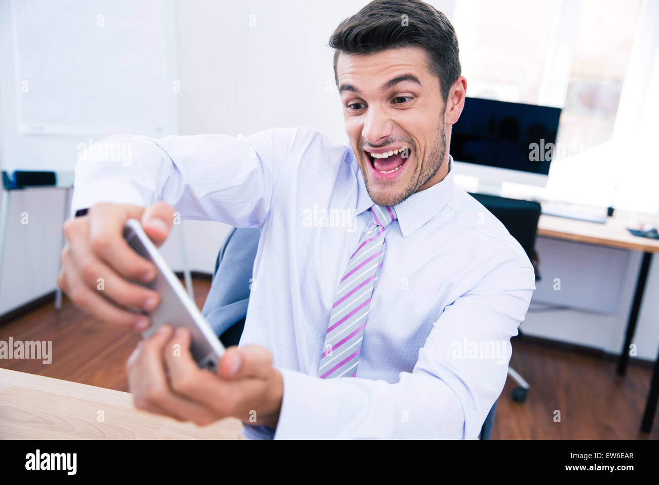 Funny businessman playing in game on the phone in office Stock Photo ...