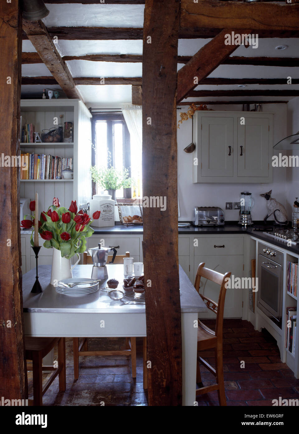 Red tulips on table set for breakfast in small cottage kitchen with ...
