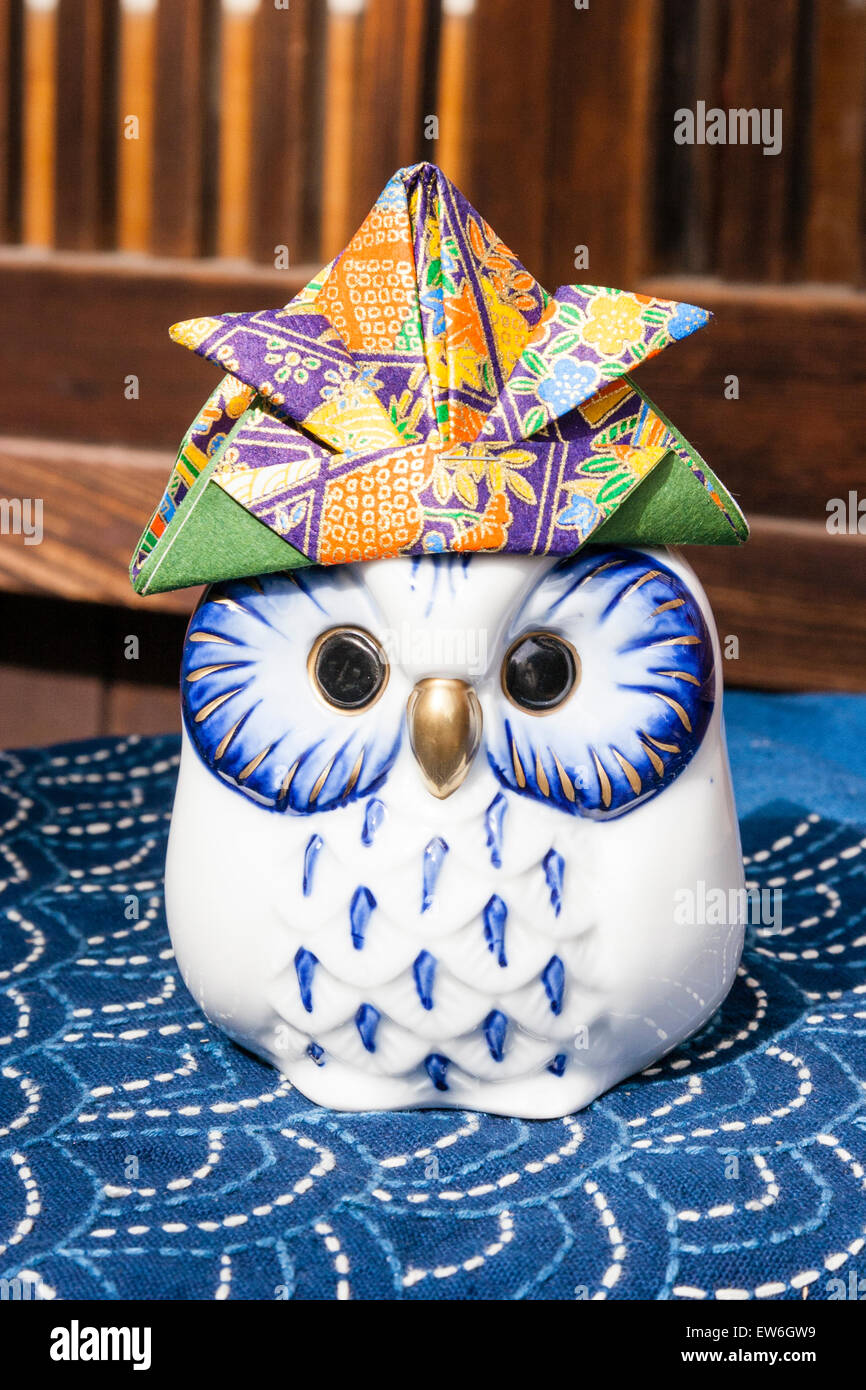 Japan, Kurashiki. Painted ceramic owl with origami paper hat stood on ...