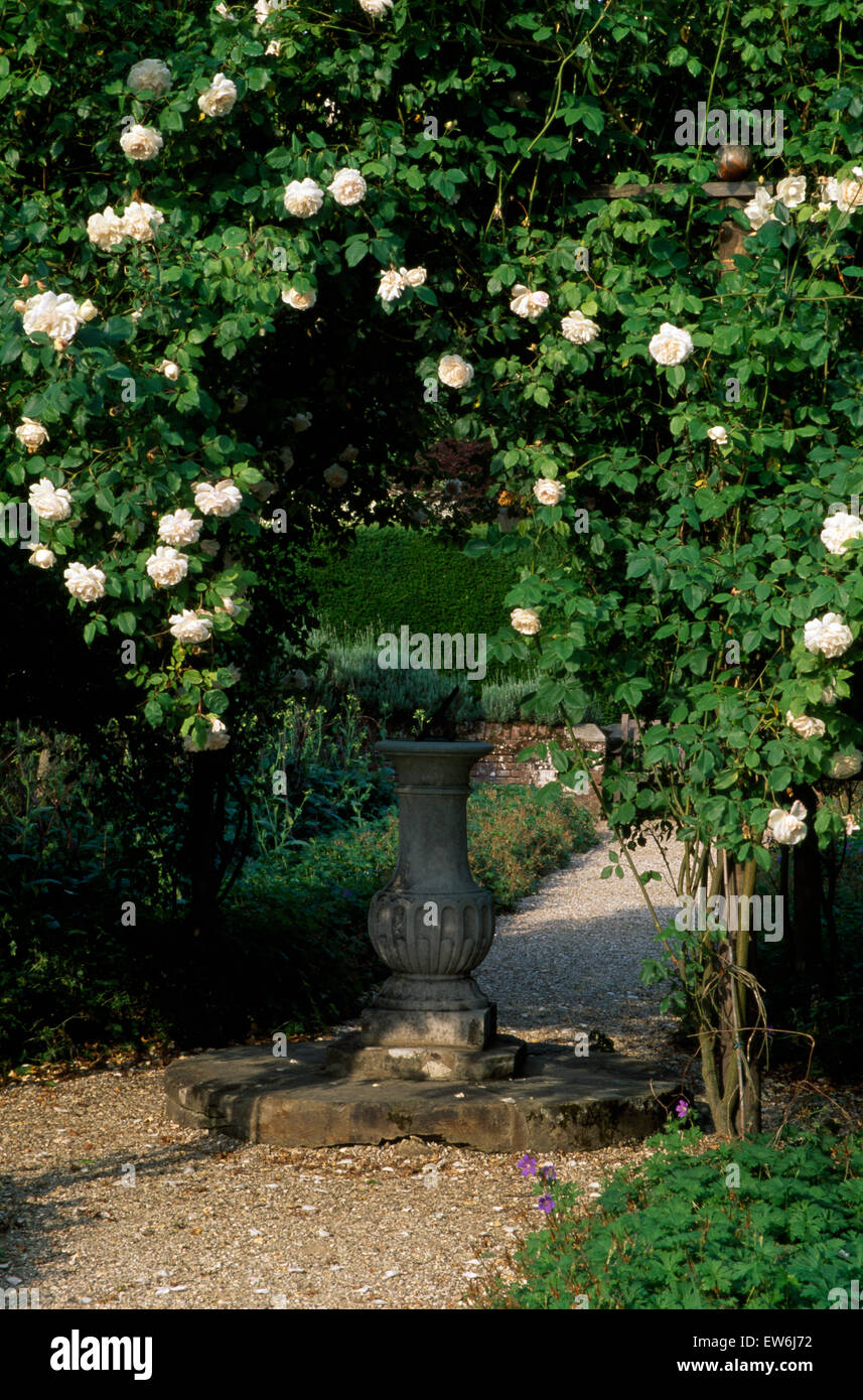 Stone sundial below white rose arch in country garden Stock Photo - Alamy