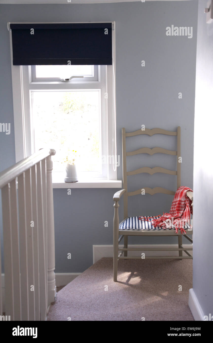 Painted ladder back chair besidew window with dark blind on a small ...