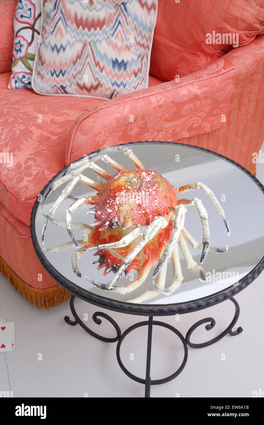 Spider crab shell on glass+metal side table beside red armchair Stock ...