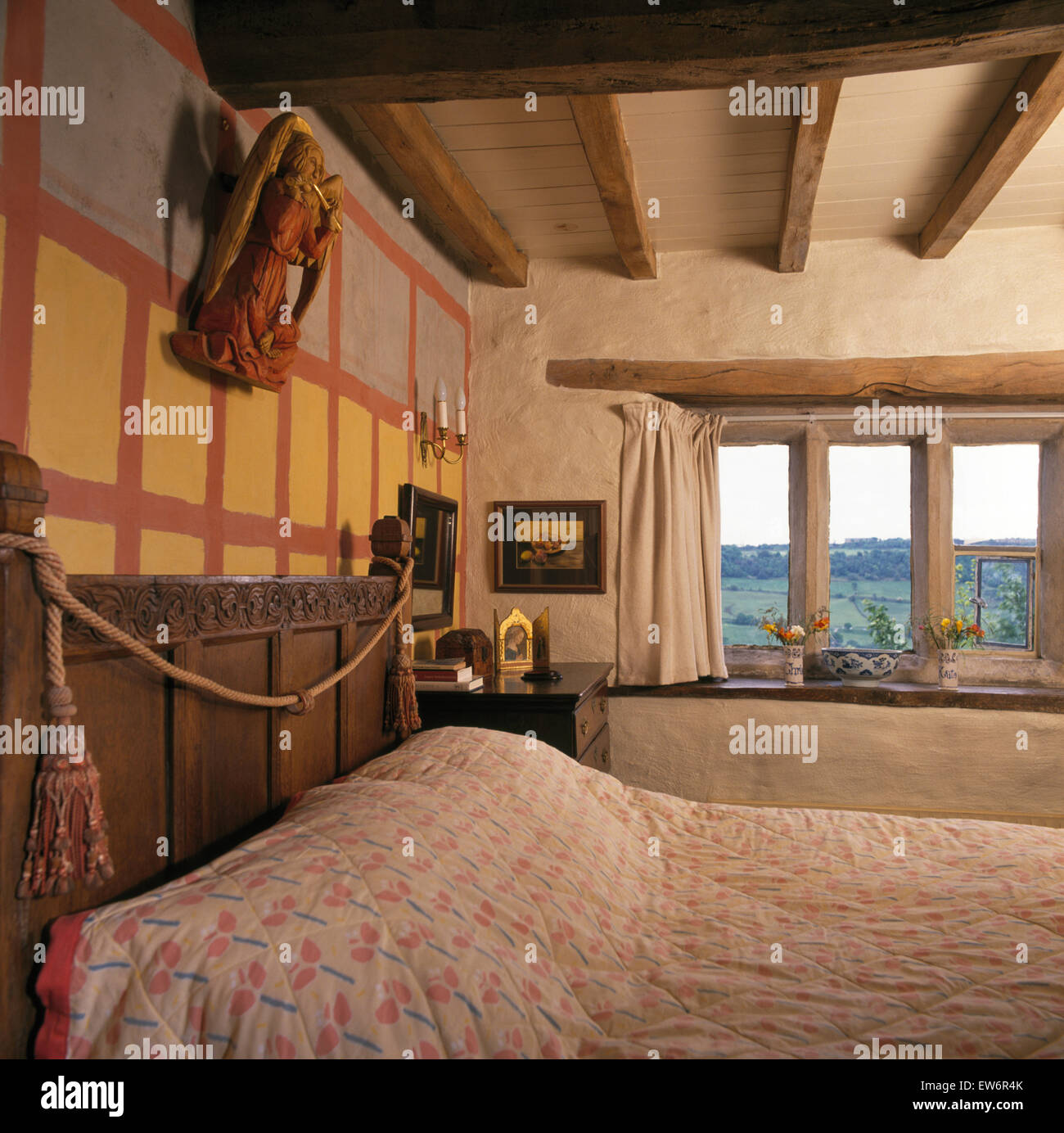 Angel statue on wall above wooden bed decorated with a silk cord in ...