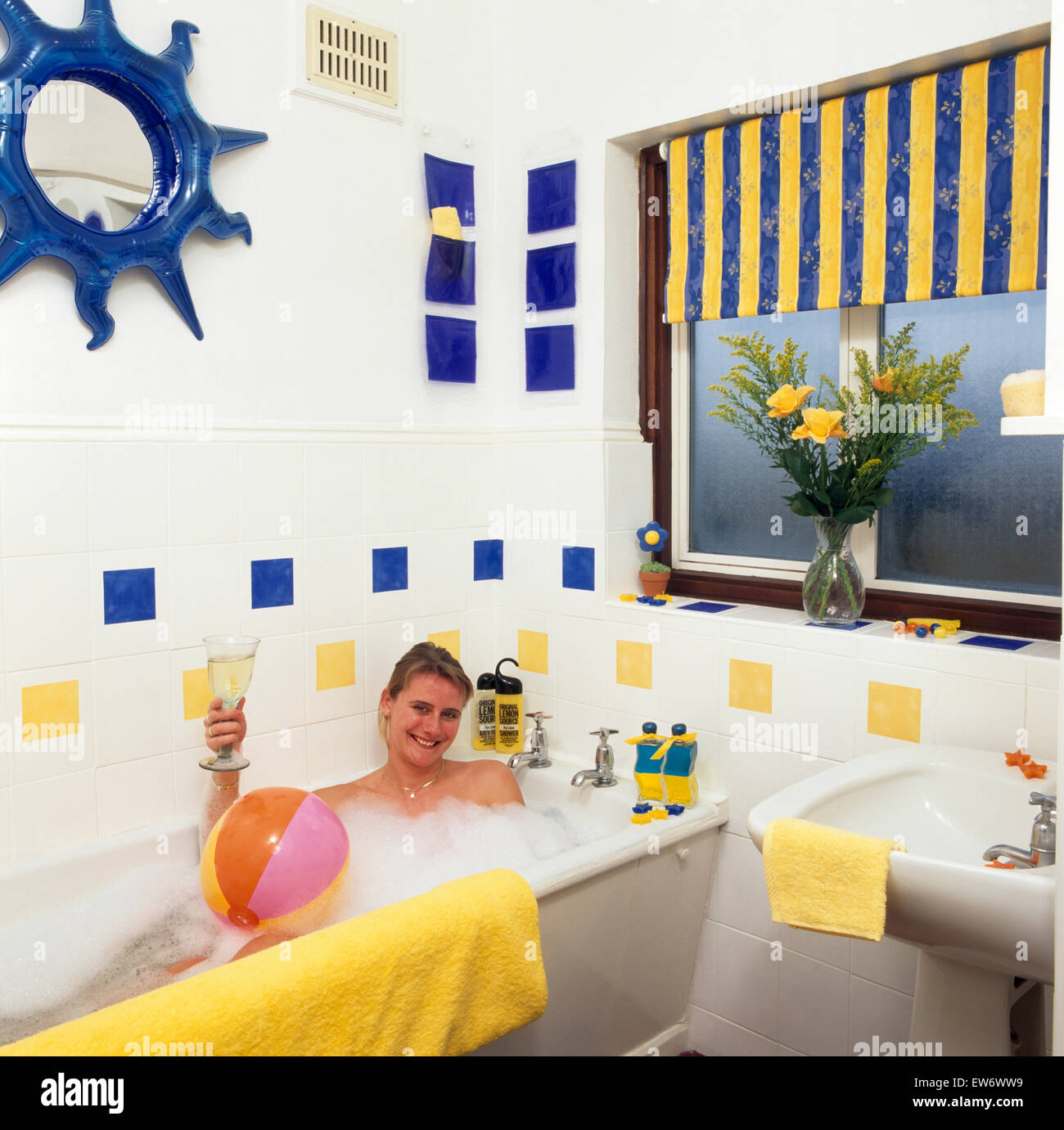 Woman drinking a glass of champagne in a bubble bath in a nineties ...