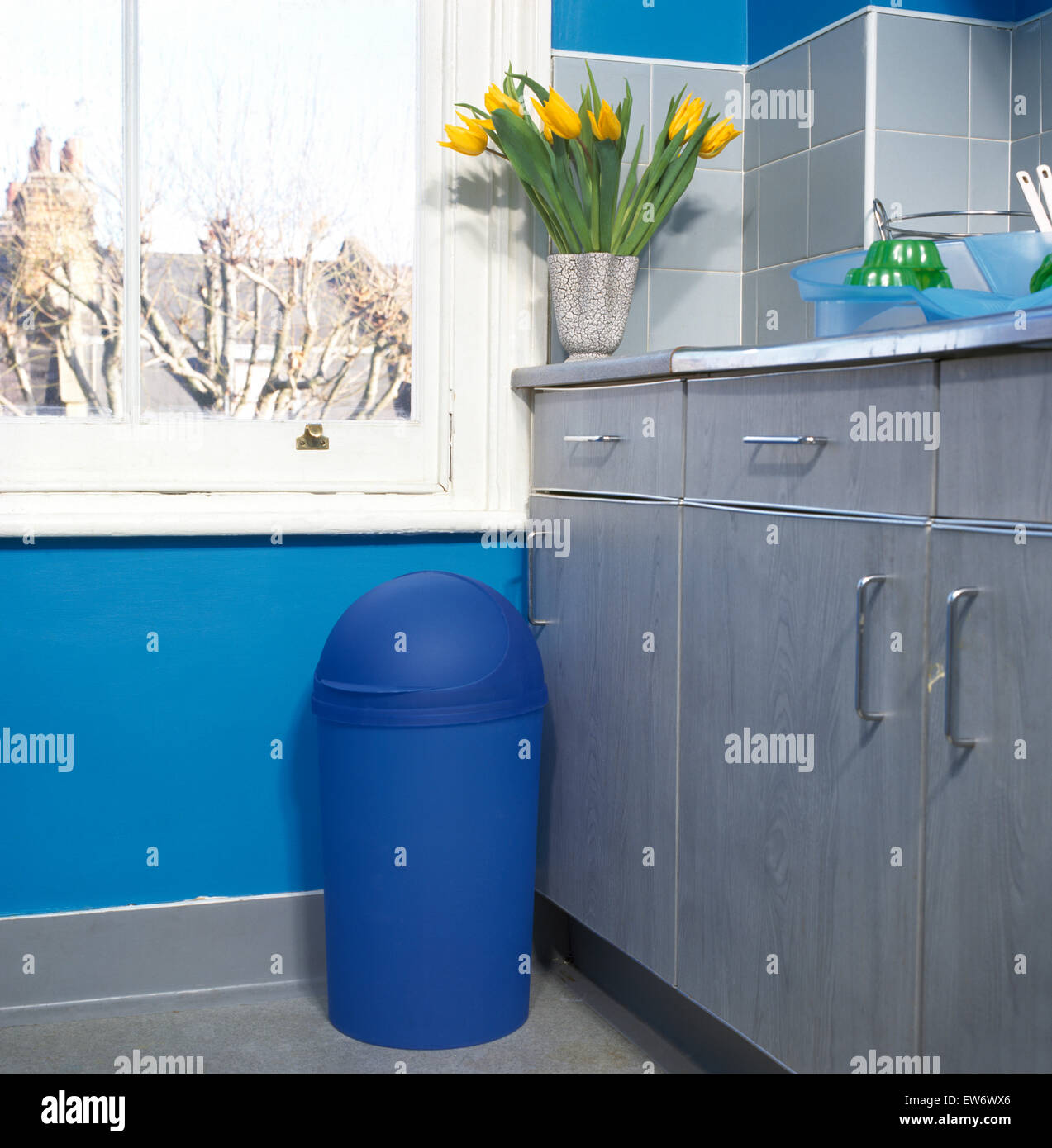 Bright blue bin in economy style nineties kitchen with silver painted ...