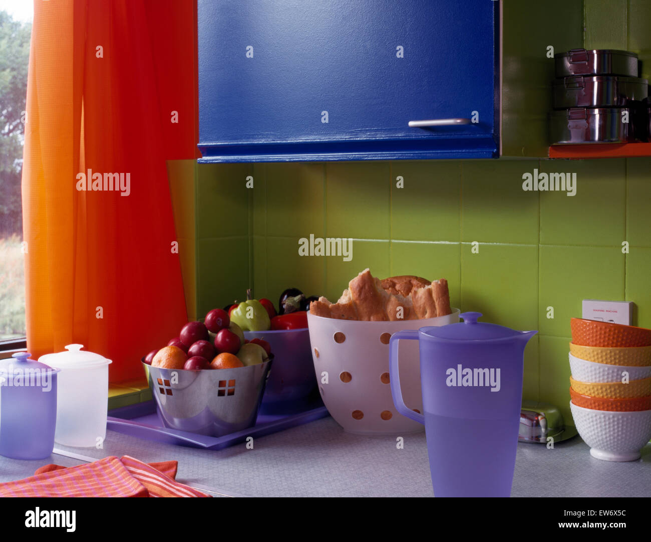 Close-up of colorful plastic pots and bowls on kitchen worktop below ...