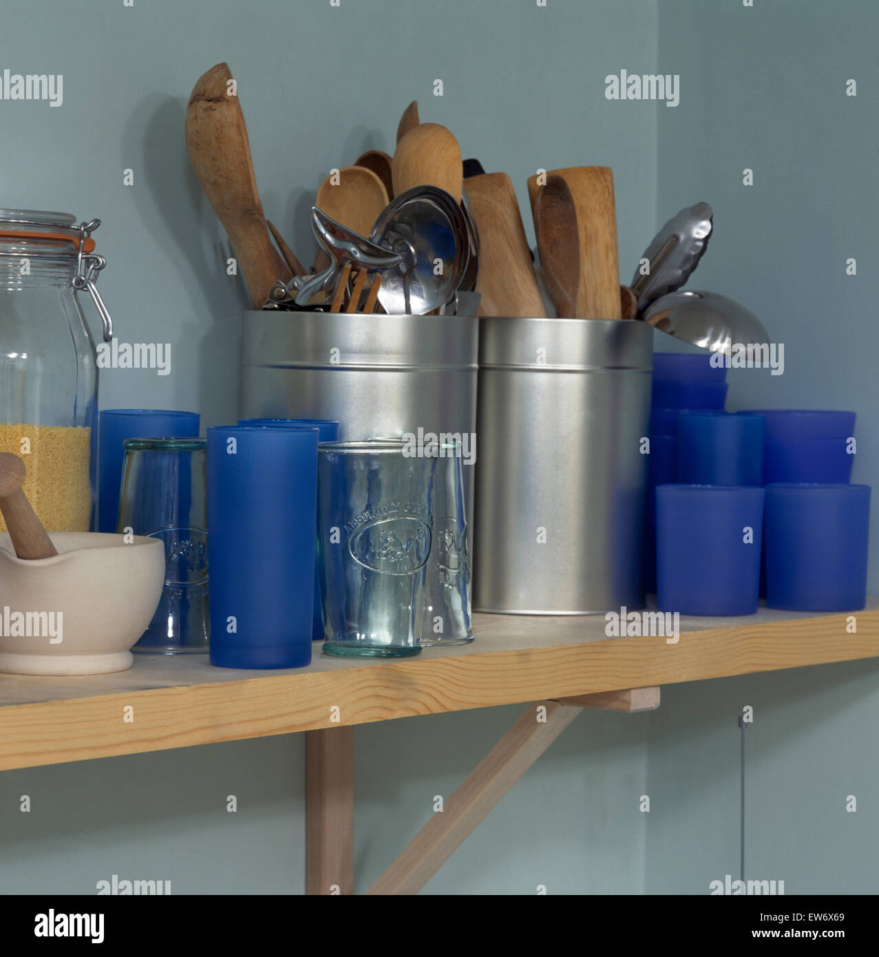 Close-up of blue plastic beakers on a wooden shelf with utensils in ...
