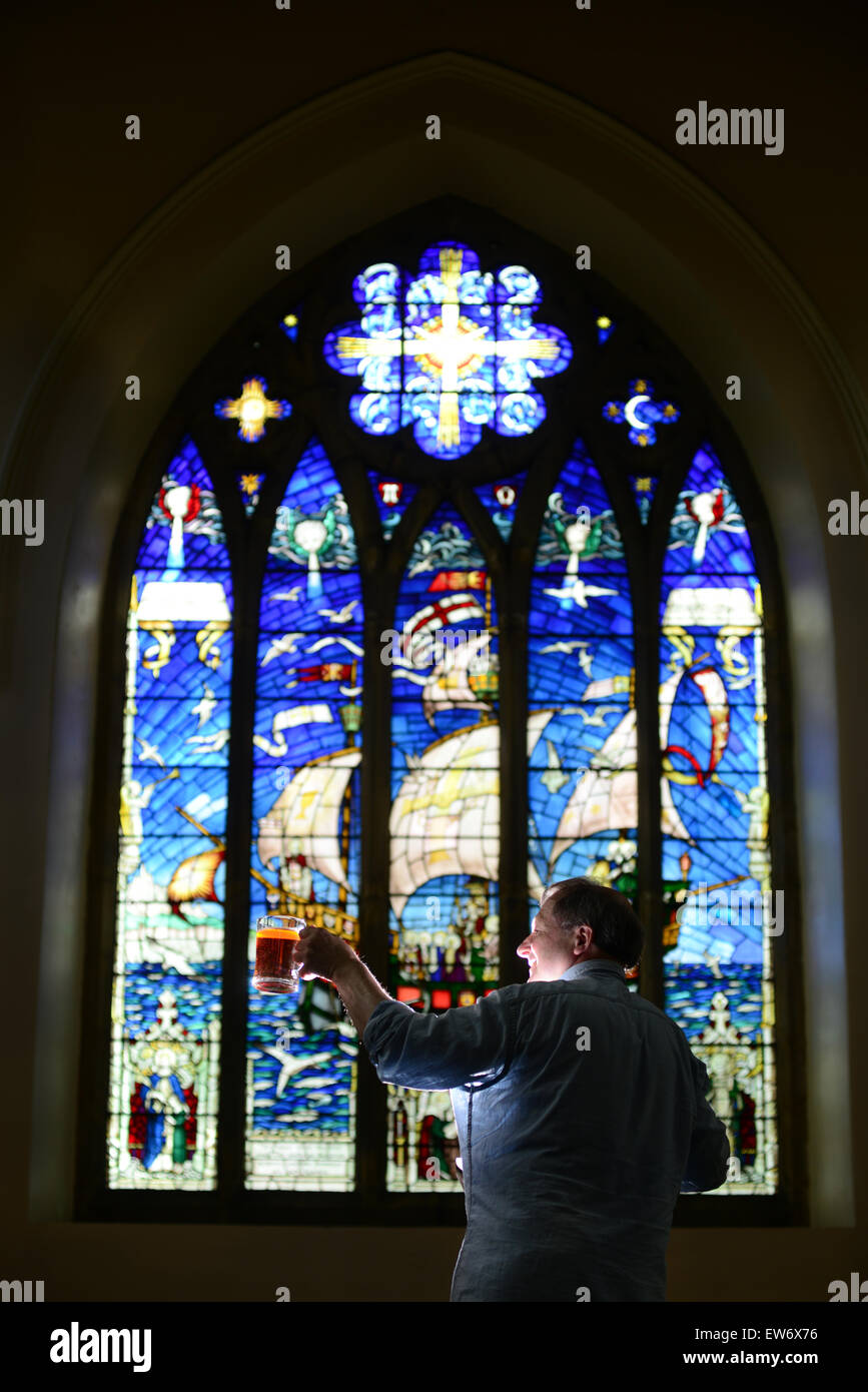 A man lifting a pint of ale in front of a stained glass window. Picture ...