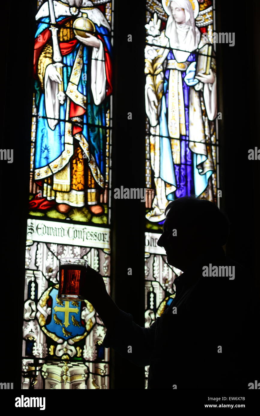 A man lifting a pint of ale in front of a stained glass window. Picture ...