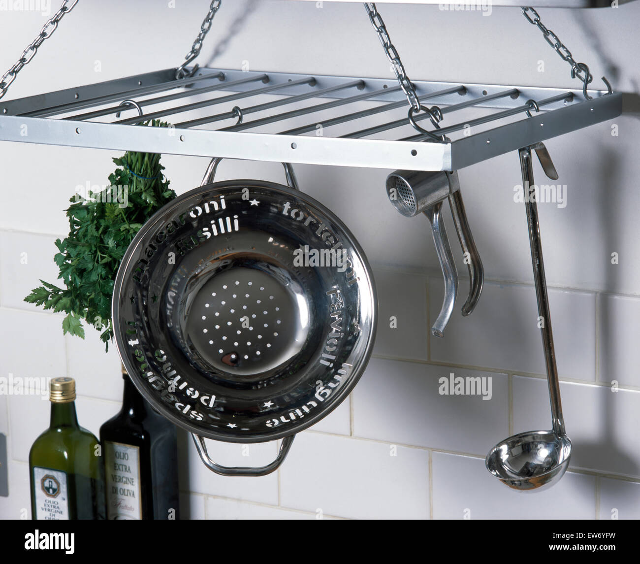 Stainless steel colander with a ladle and garlic press hanging off a ...