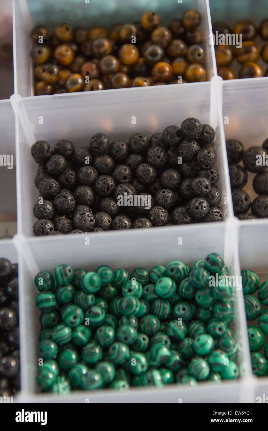 colored beads pearls stones in separated in plastic containers for ...