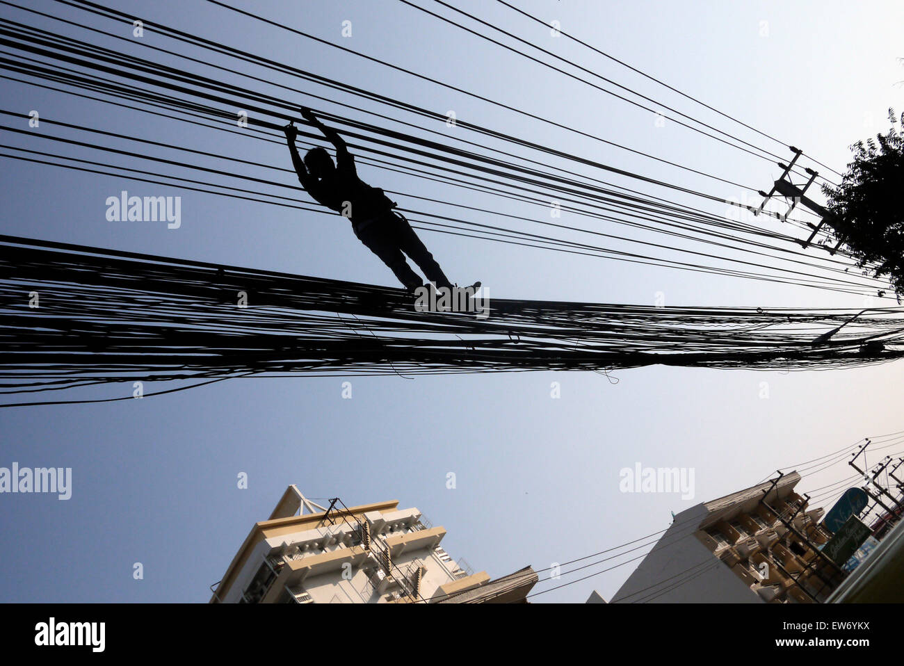 Electrical cable fitter working in a dangerous situation above a city ...