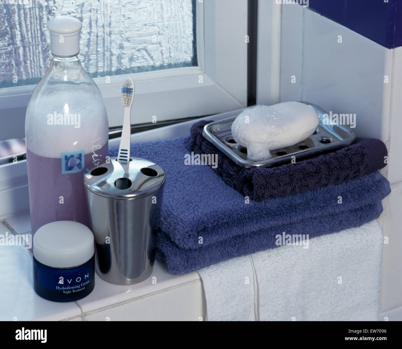 Close-up of a chrome toothbrush holder on windowsill with a folded blue ...