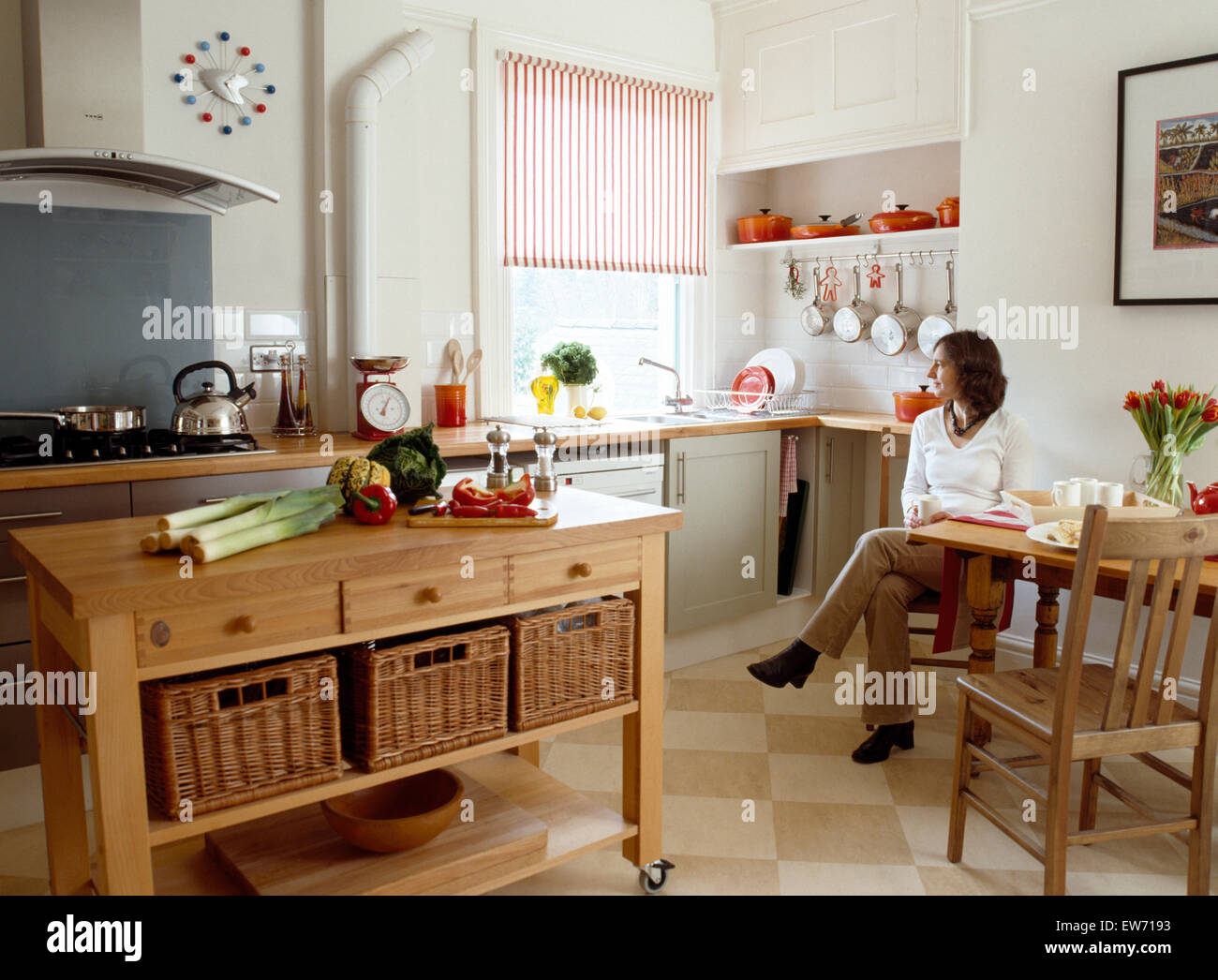 Woman sitting at table in modern kitchen FOR EDITORIAL USE ONLY Stock ...