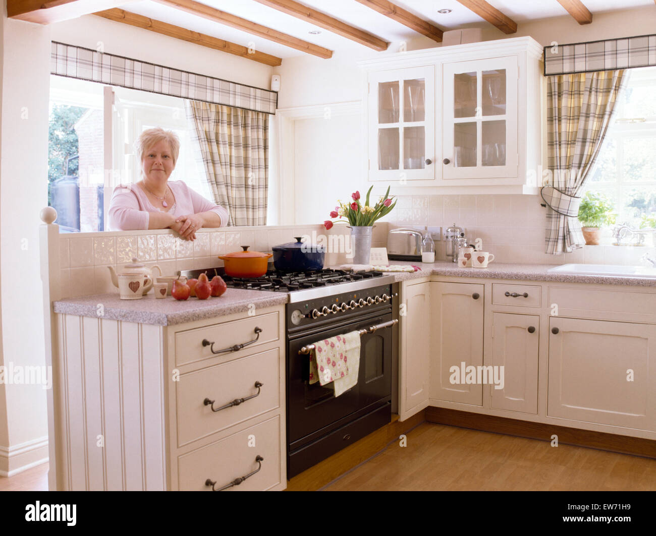 Portrait of woman looking through window into cottage kitchen FOR ...